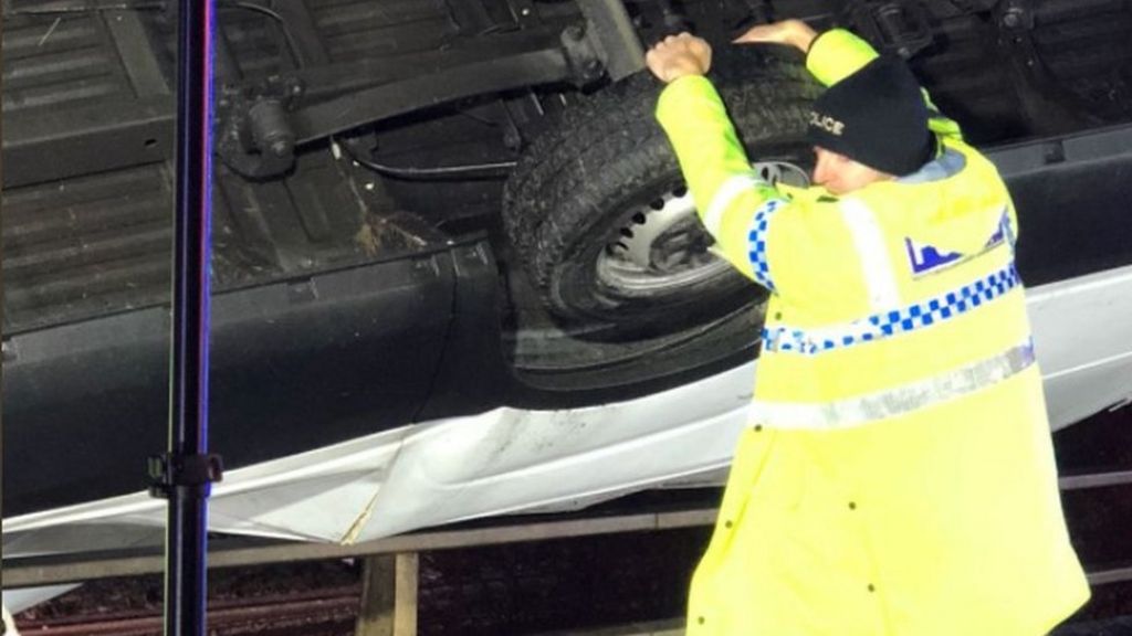 A police officer held on to a van to stop it falling as it teetered on ...